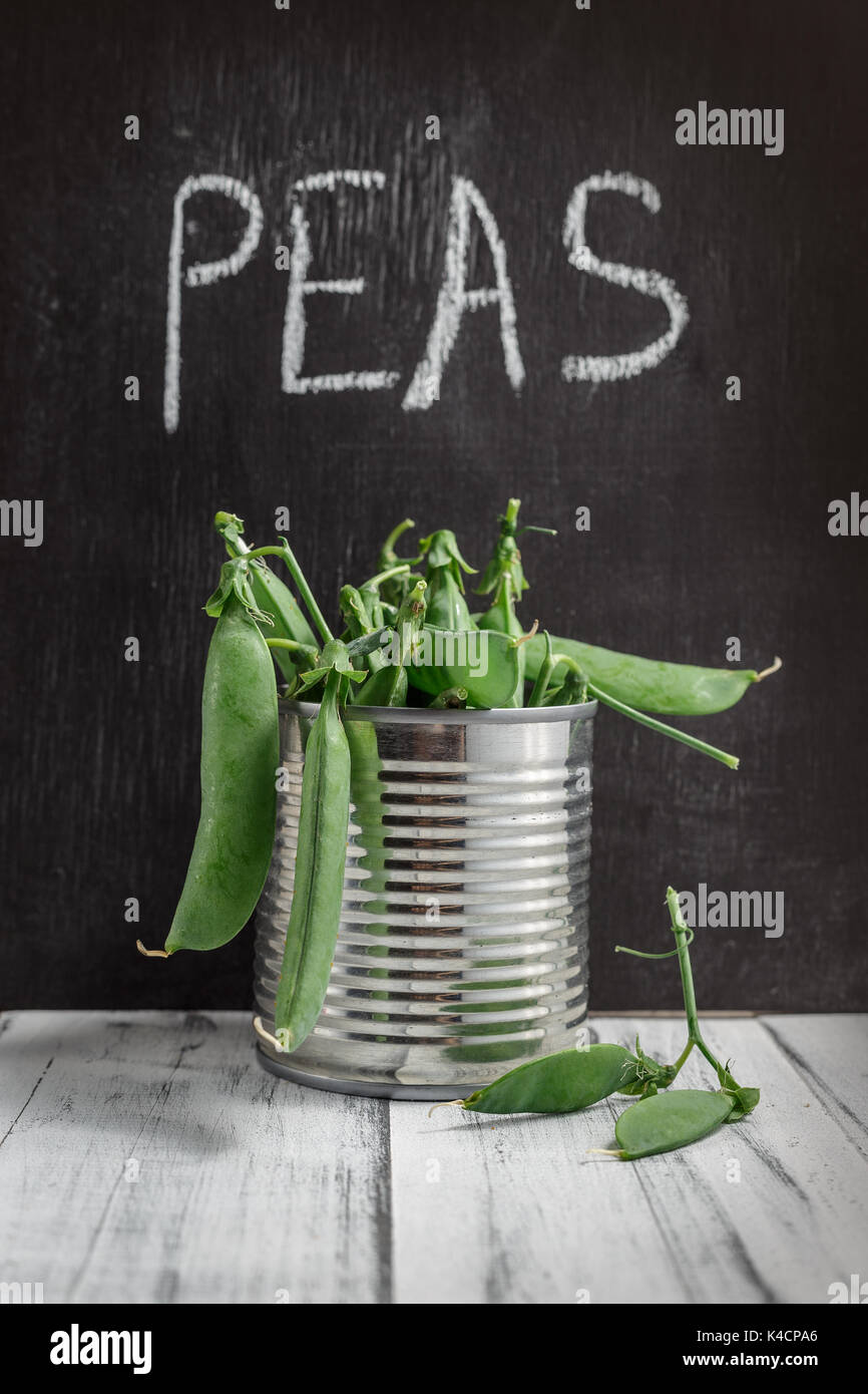 Green peas in metal can over black chalk board, the word peas written ...