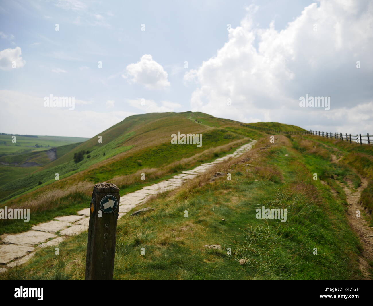 Wooden footpath marker on a pathway, with the peak of Mam Tor in the ...