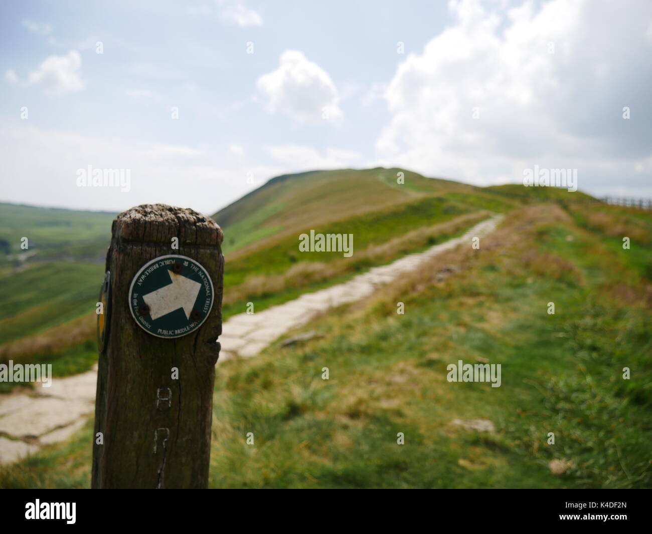 Wooden footpath marker on a pathway, with the peak of Mam Tor in the ...