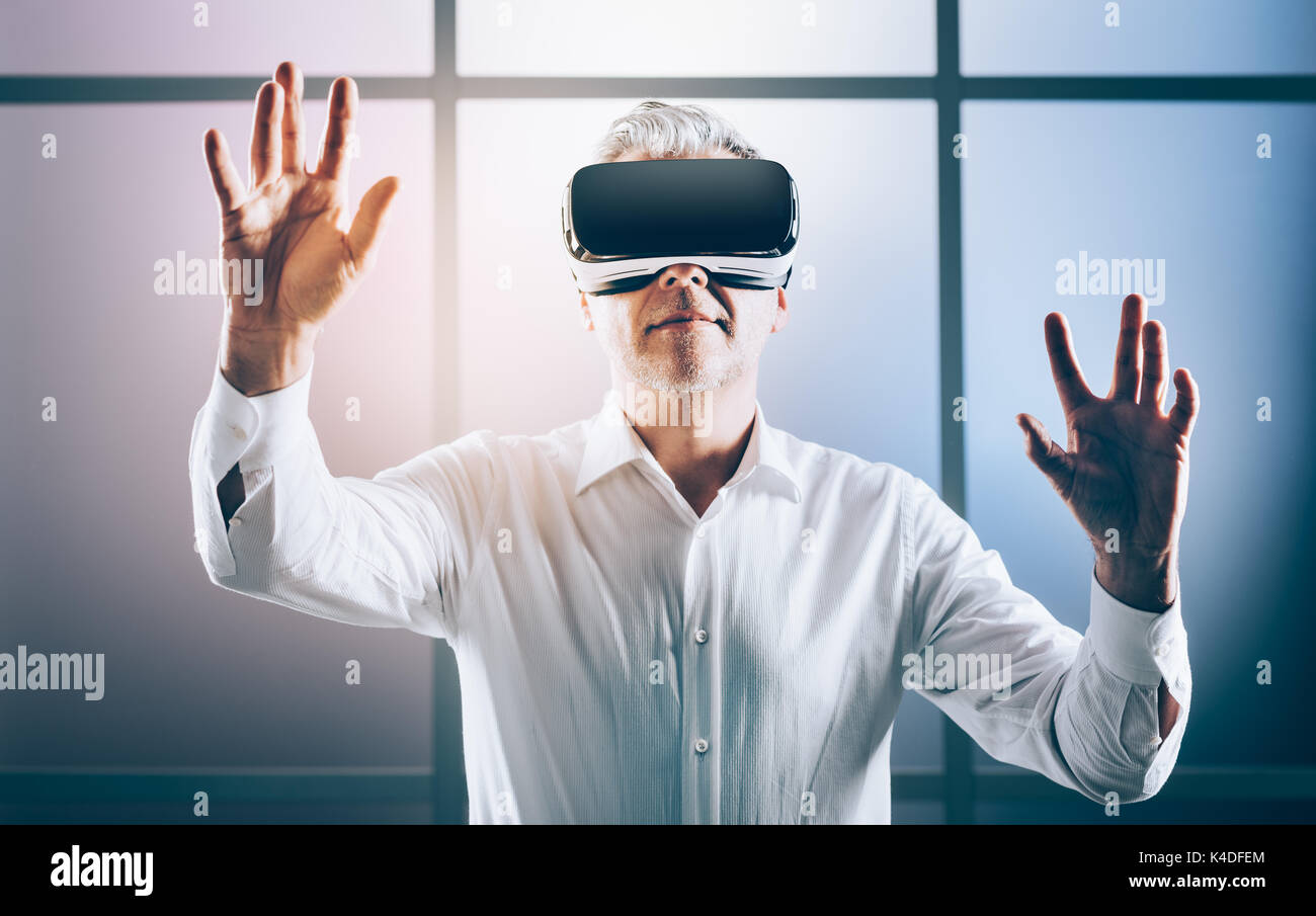 Mature man wearing a VR headset and interacting with a virtual reality ...