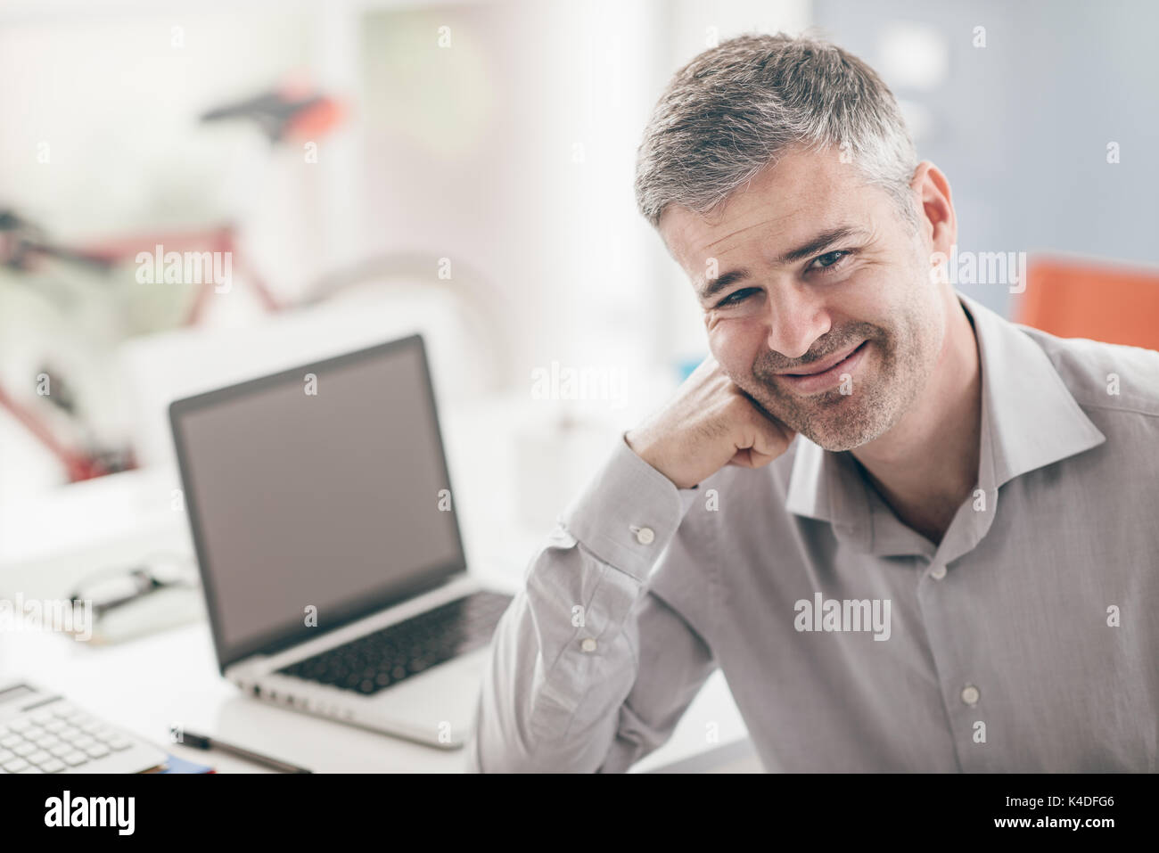 Confident office worker sitting at office desk and working with a ...