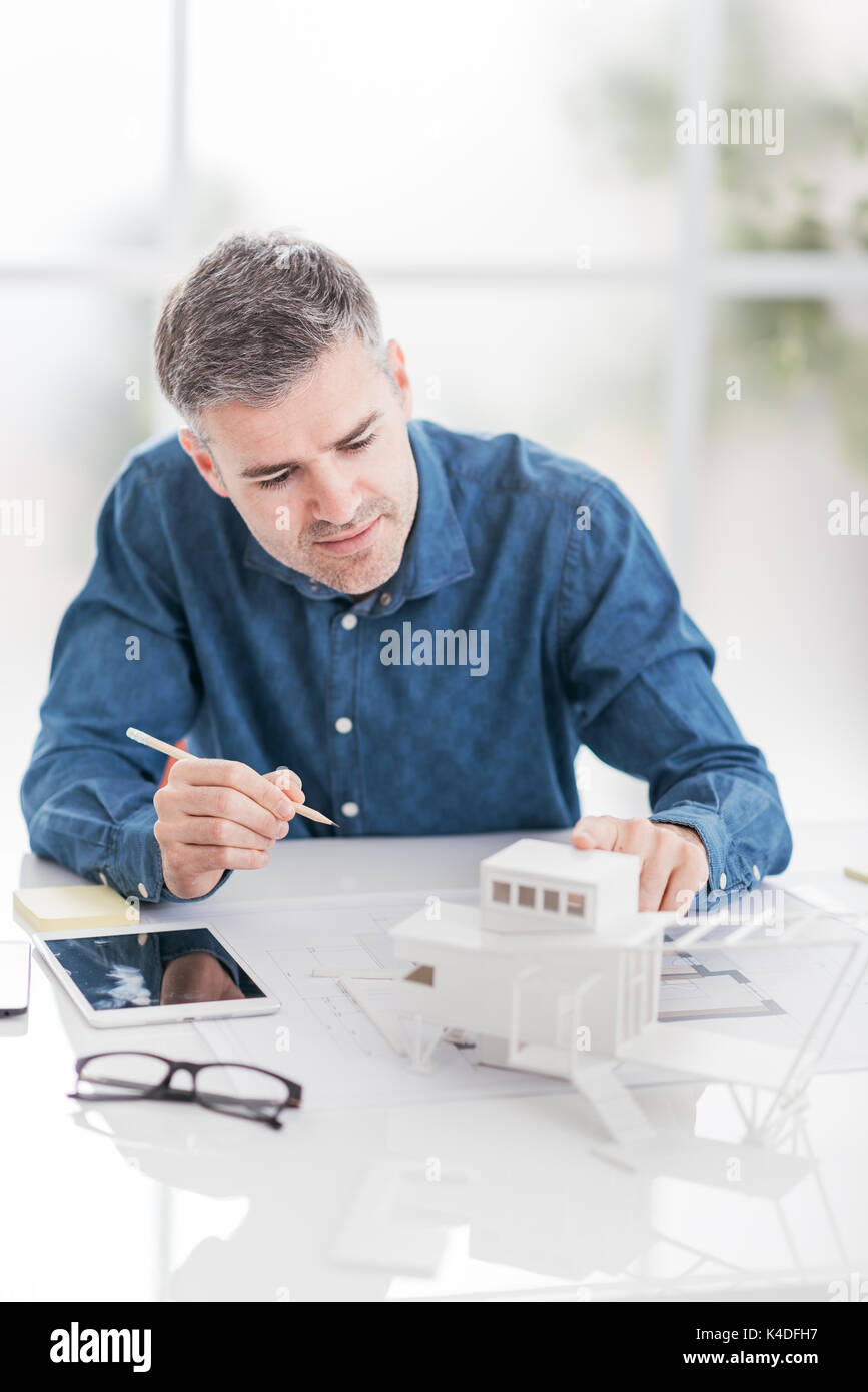Architect checking an architectural model and drawing on a blueprint ...