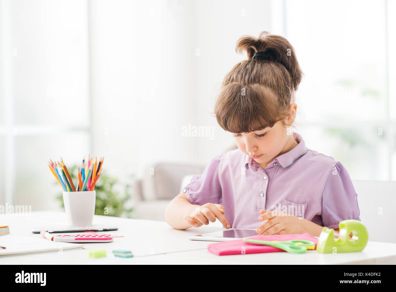Cute girl using a digital tablet and doing her homework, technology and ...