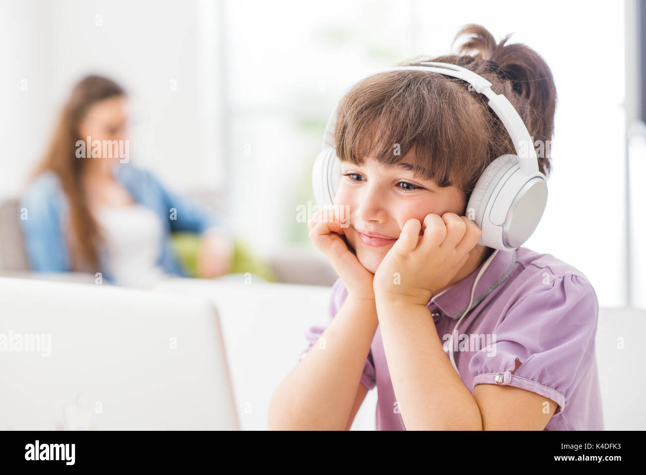 Happy cute girl watching videos streaming online on her laptop at home ...