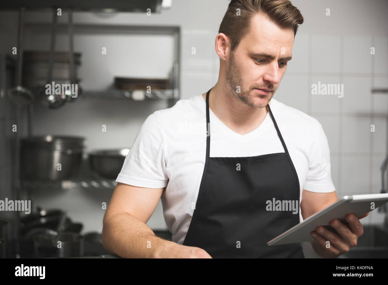 Portrait of handsome chef cooking meal holding tablet Stock Photo - Alamy