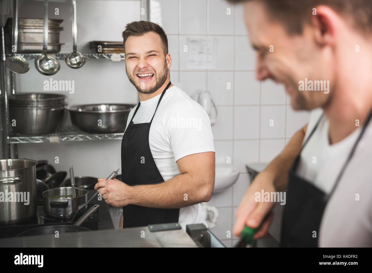 Portrait of two happy male chefs cooking in the kitchen having fun ...