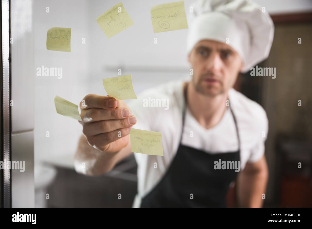 Portrait of chef reading notes sticked to glass Stock Photo - Alamy