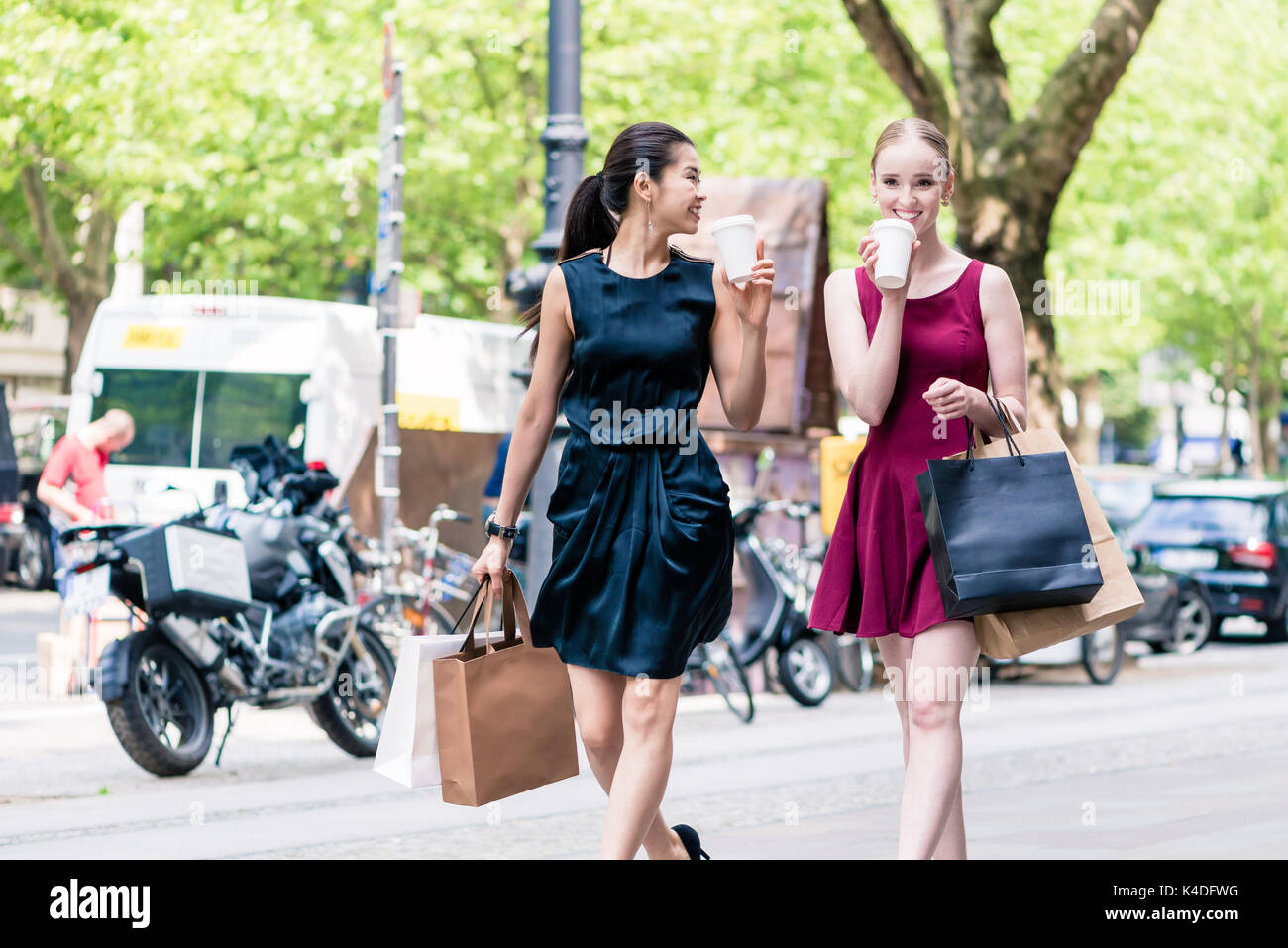 Two female best friends drinking coffee while walking downtown f Stock ...