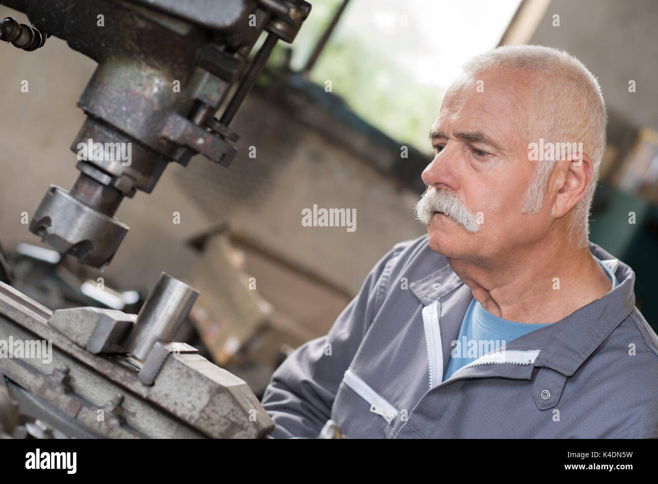 elderly worker watches processing of detail on milling machine Stock ...