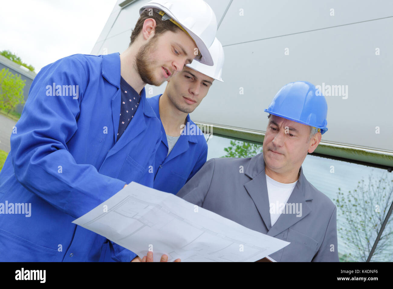 builders on a construction site holding a plan Stock Photo - Alamy