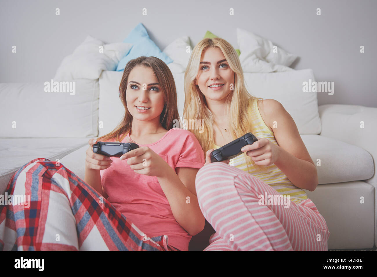 Portrait of beautiful women having pajama party playing video games ...