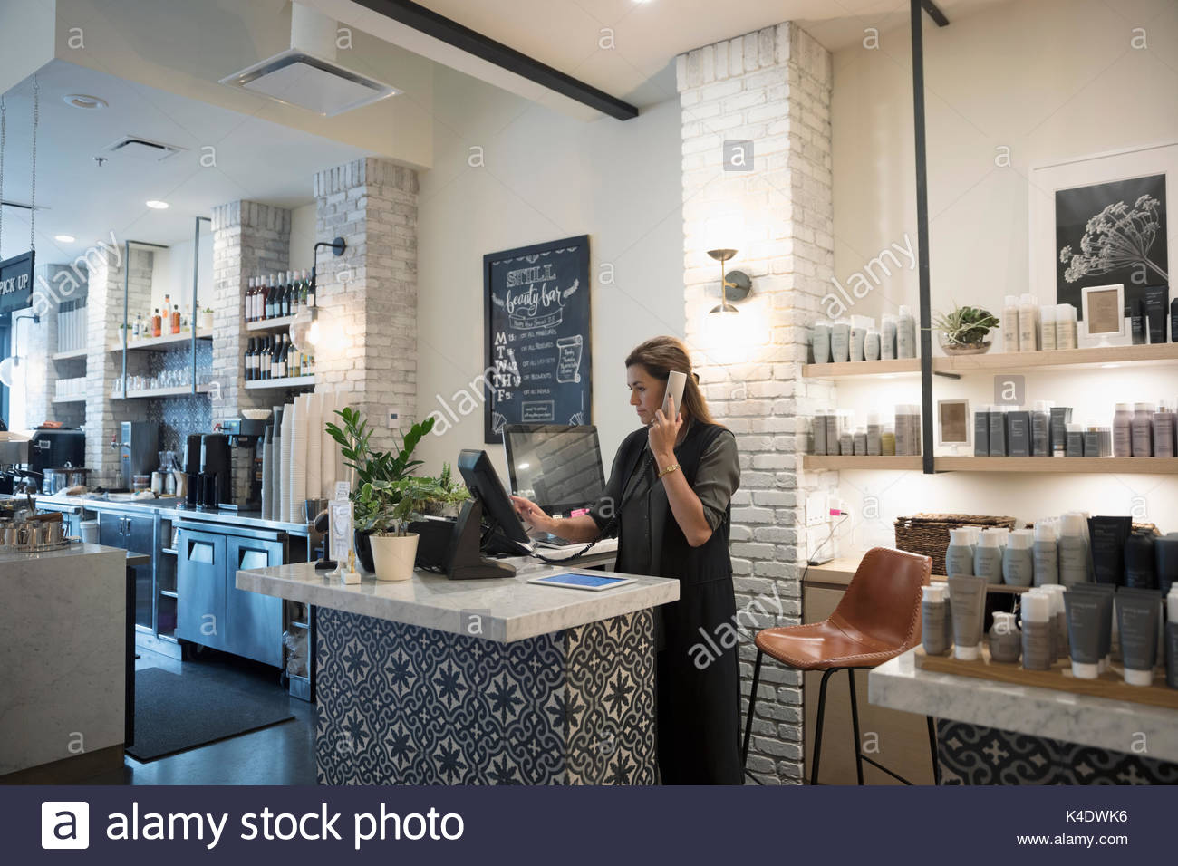 Female salon shop owner talking on telephone at computer Stock Photo ...