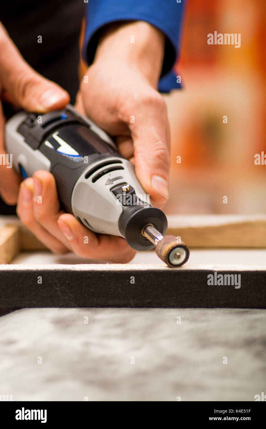 Closeup of a hardworker man using a polisher in a wooden frame, on a ...