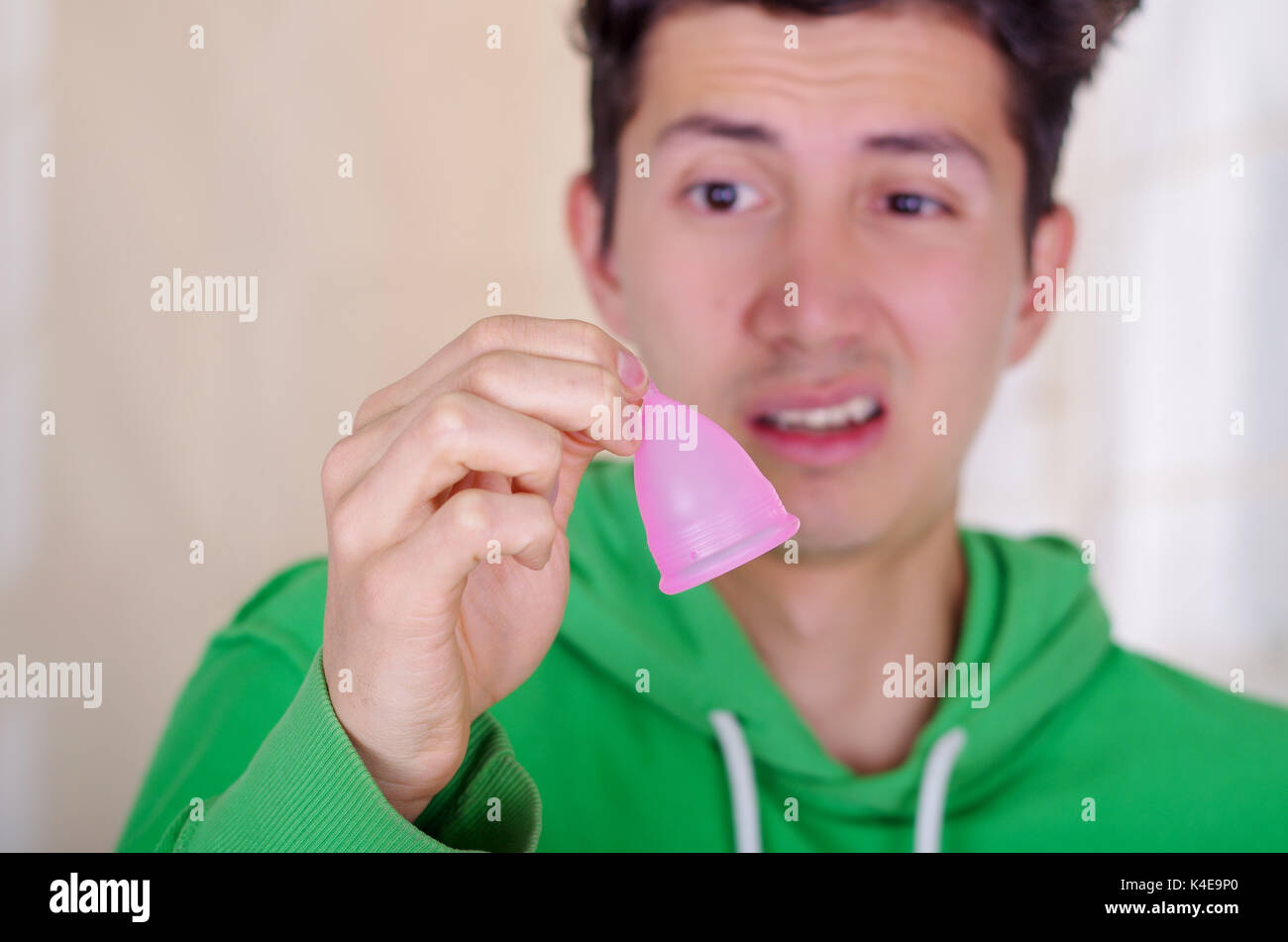 Close up of a man doing an disgusting face while is holding a menstrual ...