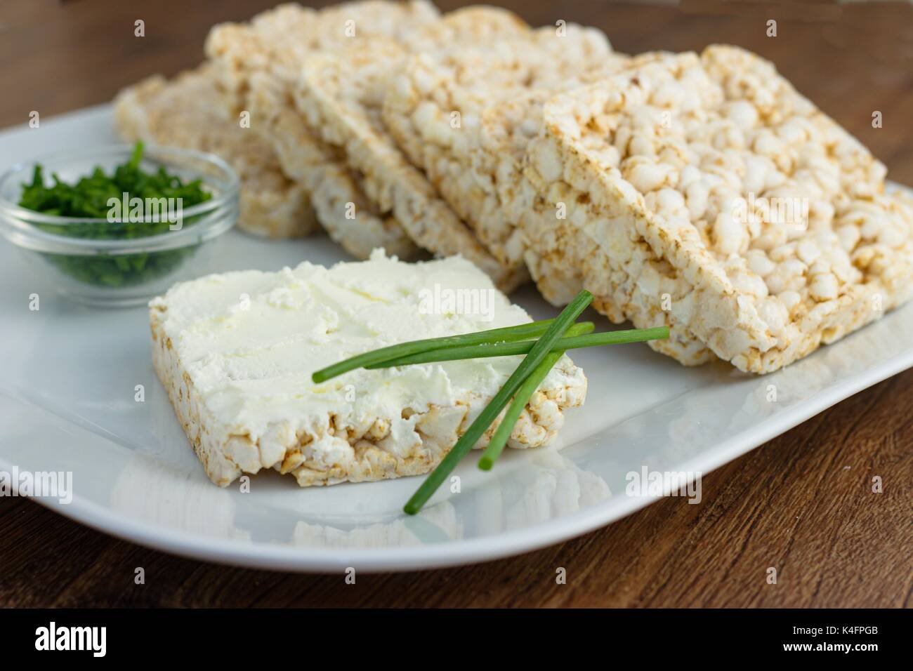 Rice cakes served with cream cheese and chives on white plate. Concept ...