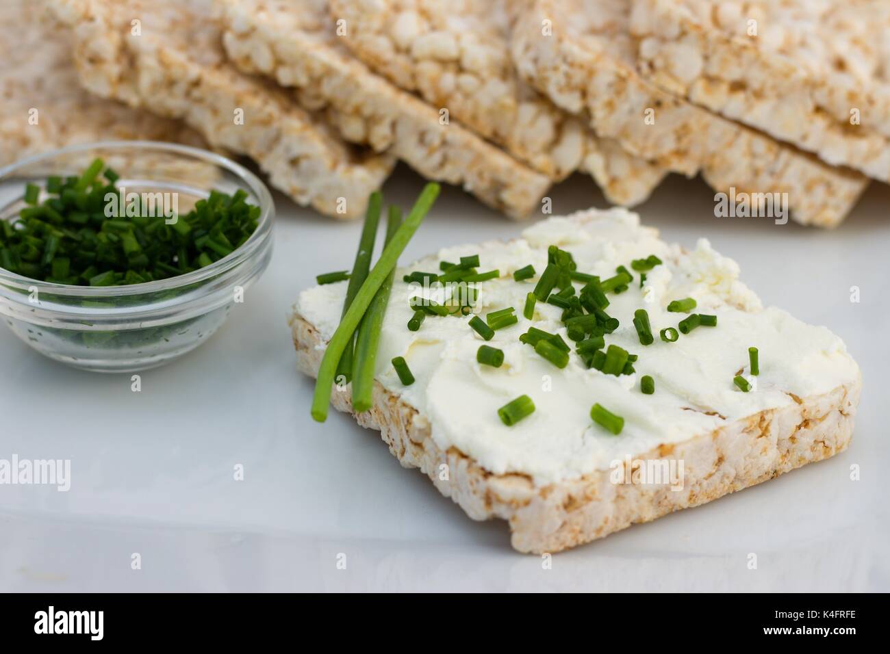 Rice cake served with cream cheese and chives on white plate. Concept ...