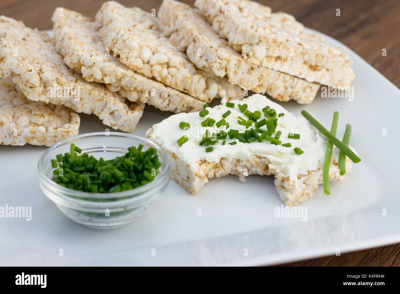 Bitten off rce cake with cream cheese and chives on white plate ...