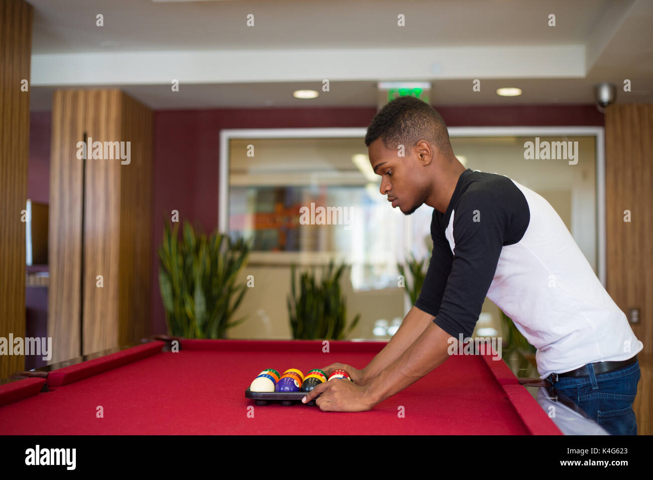 Closeup portrait, young man hanging out, playing billiards at red pool ...