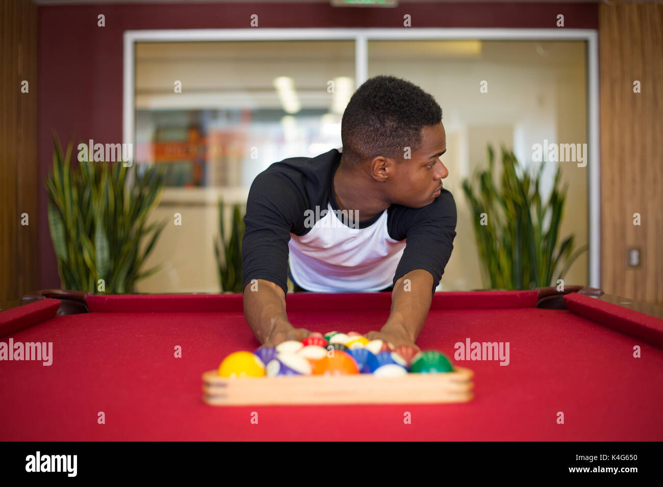 Closeup portrait, young man hanging out, playing billiards at red pool ...