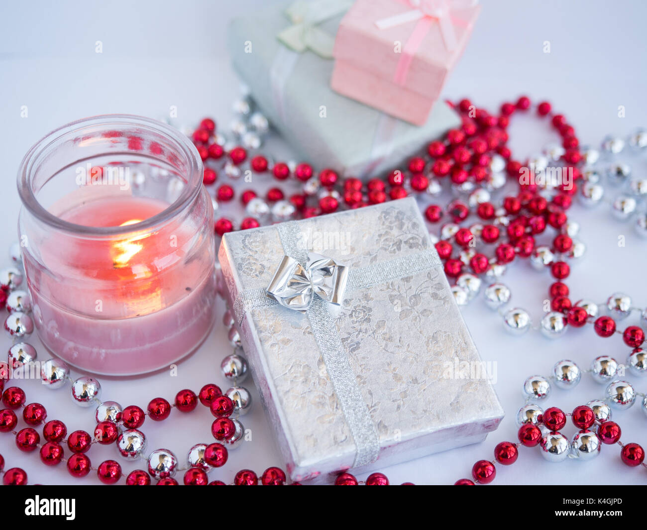 Small beautiful gift boxes with a candle decorated by beads on a white ...