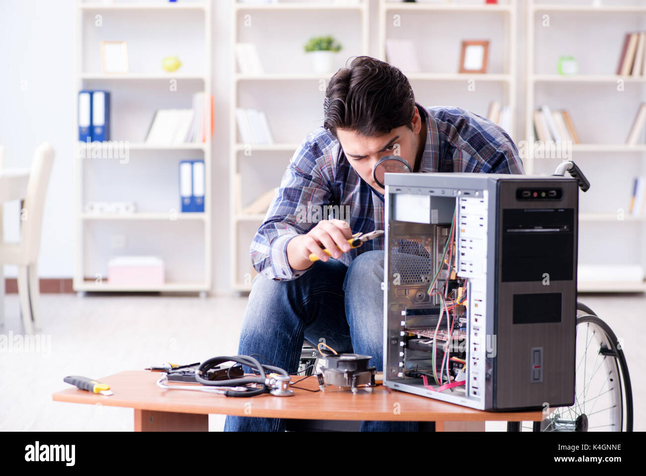 Disabled man on wheelchair repairing computer Stock Photo - Alamy