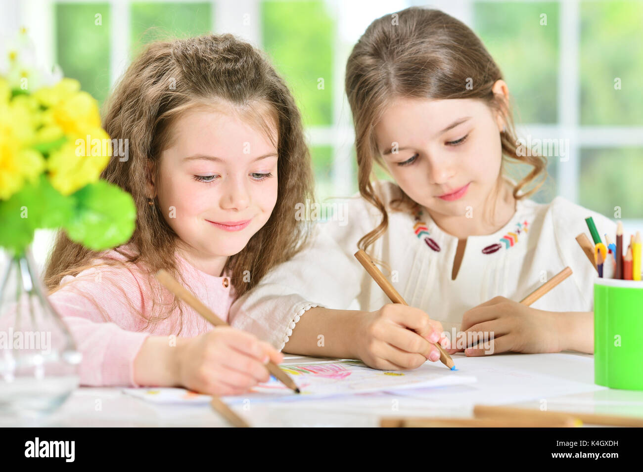 Two cute little girls drawing with pencils Stock Photo - Alamy