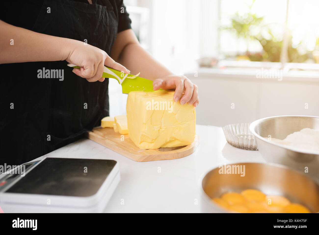 Cropped image of female chef cutting butter in kitchen Stock Photo - Alamy