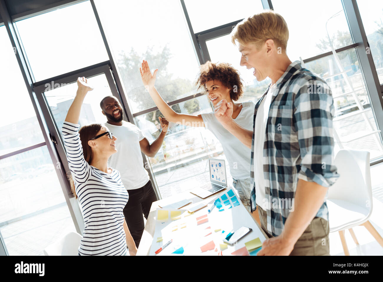 Positive young colleagues feeling happy after their successful project ...