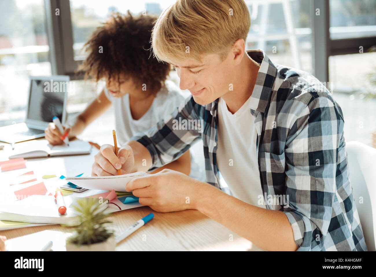 Positive young male student studying with his groupmate Stock Photo - Alamy