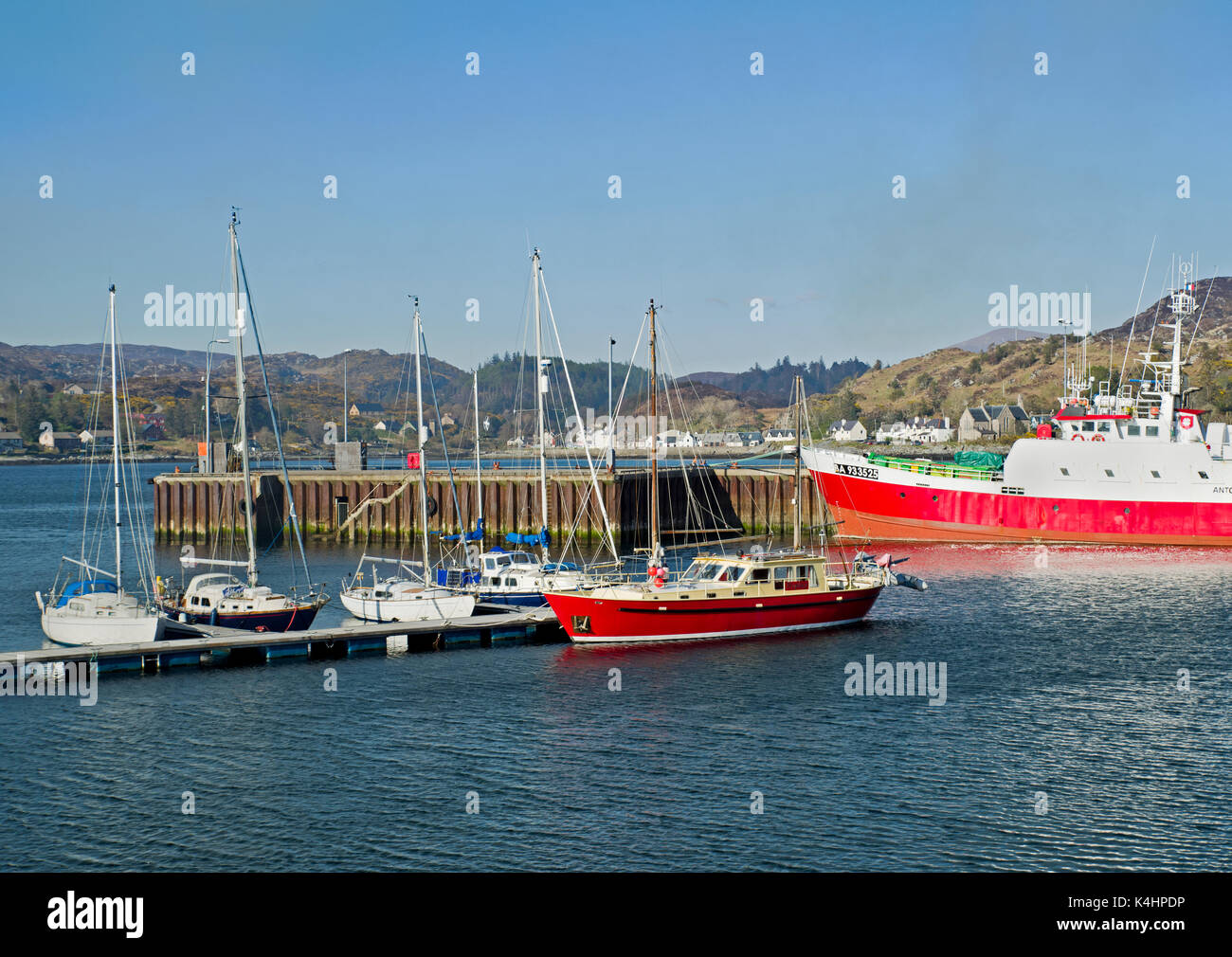Small boats moored in Lochinver harbour on a calm and sunny evening ...