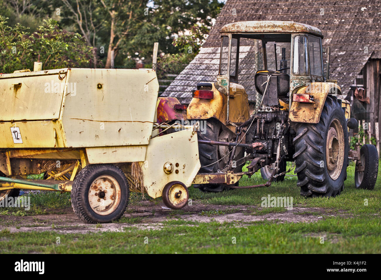 very old straw press and yellow tractor Stock Photo - Alamy