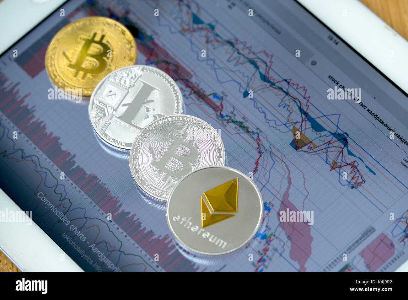 E-coins set on tablet computer with charts on screen Stock Photo - Alamy