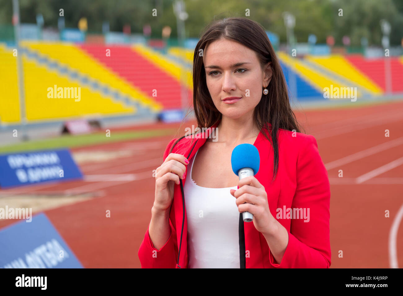 Pretty journalist is reporting from the stadium for TV show Stock Photo ...