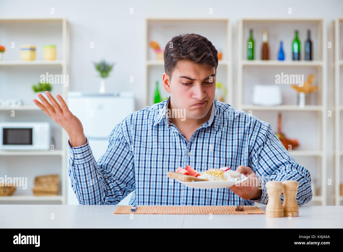 Young husband eating tasteless food at home for lunch Stock Photo - Alamy