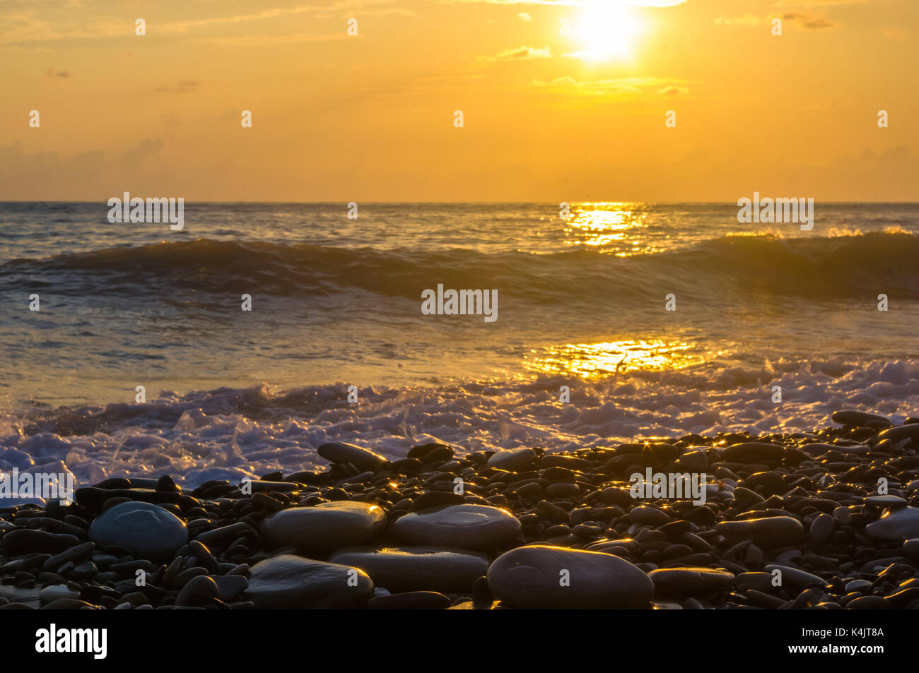 Summer sea sunset on the pebble beach, the sun, waves and clouds ...