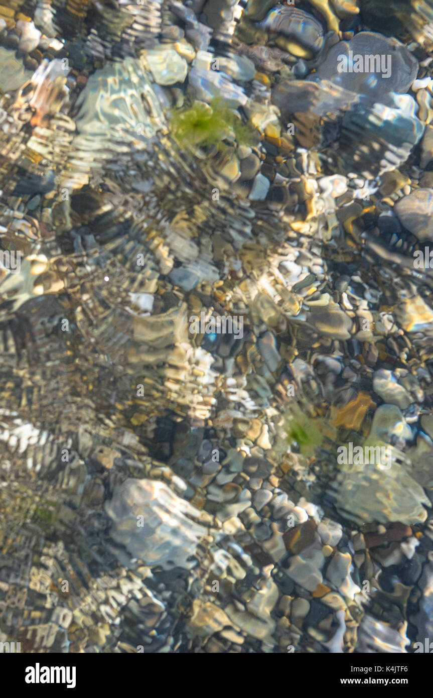 sea pebble beach with multicoloured stones, transparent waves with foam ...