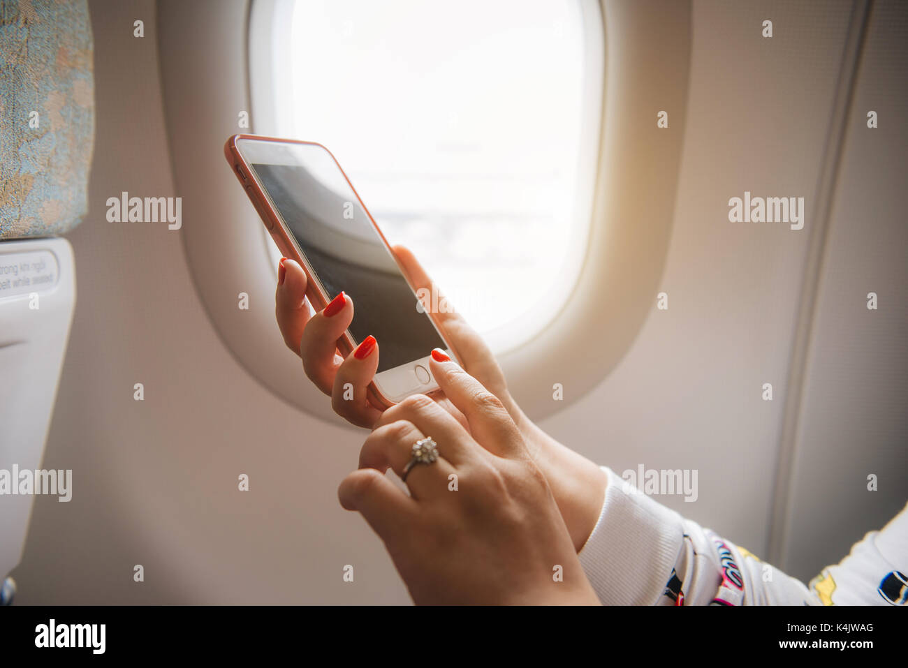 Woman hand using smart phone on airplane. Female traveler using smart ...