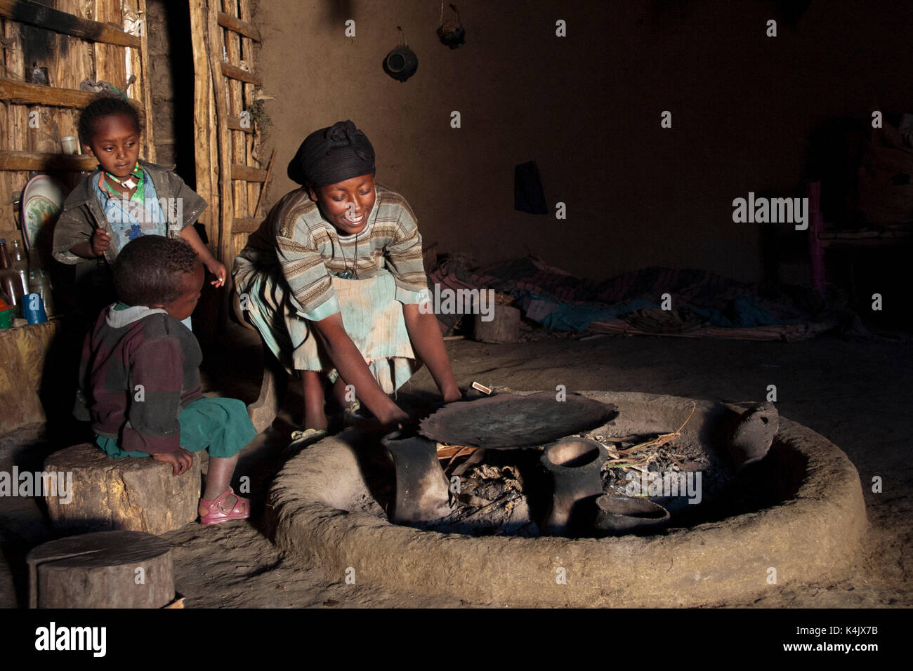 A woman lighting a fire in her home so she can cook dinner, Ethiopia ...