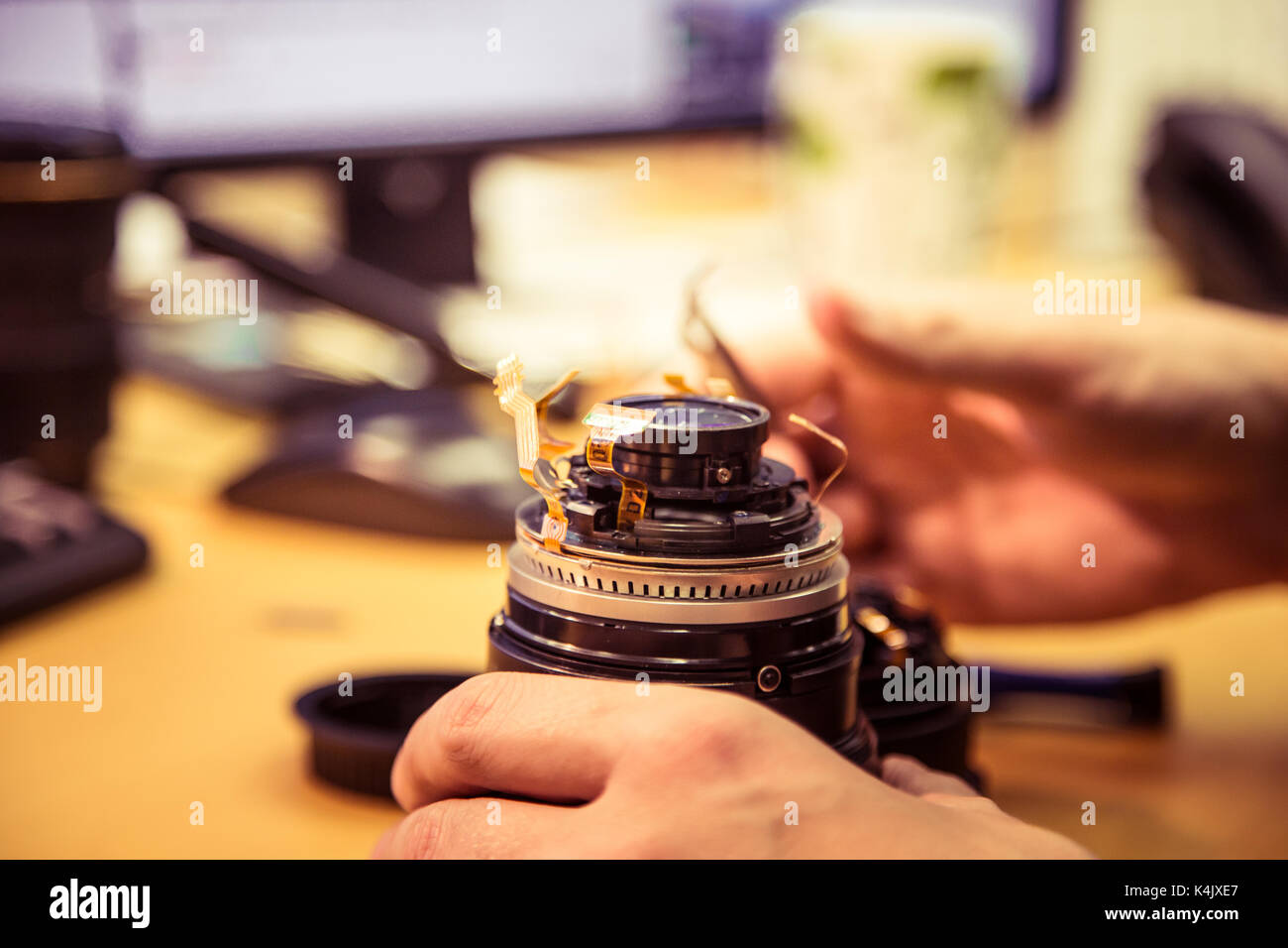 A man fixing photo camera lens on an office table Stock Photo - Alamy