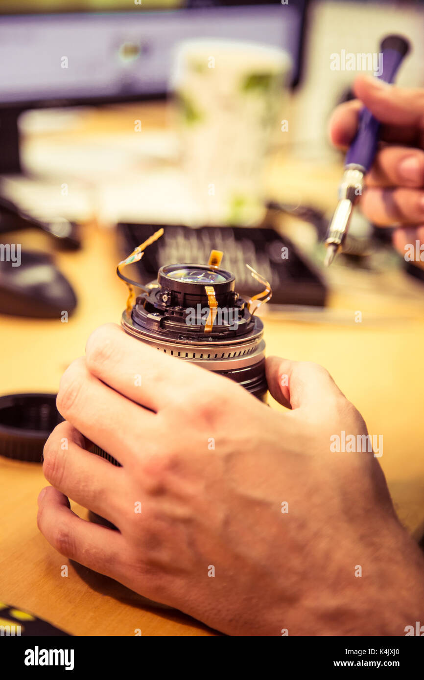 A man fixing photo camera lens on an office table Stock Photo - Alamy