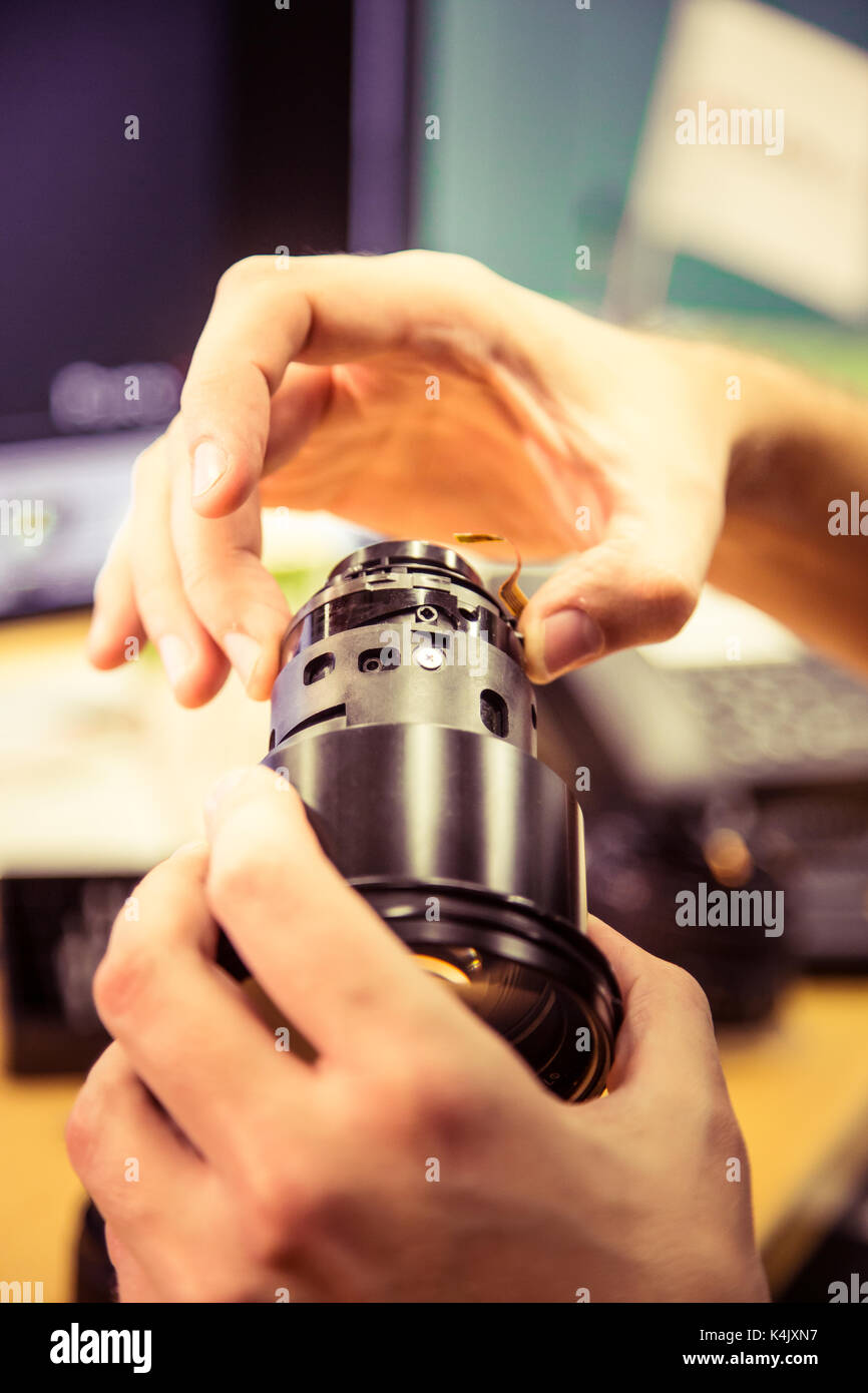 A man fixing photo camera lens on an office table Stock Photo - Alamy