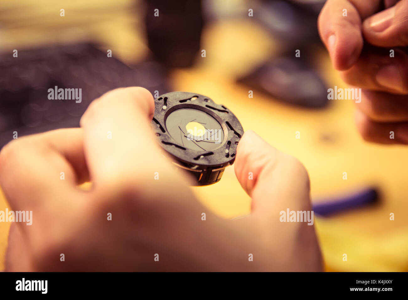 A man fixing photo camera lens on an office table Stock Photo - Alamy