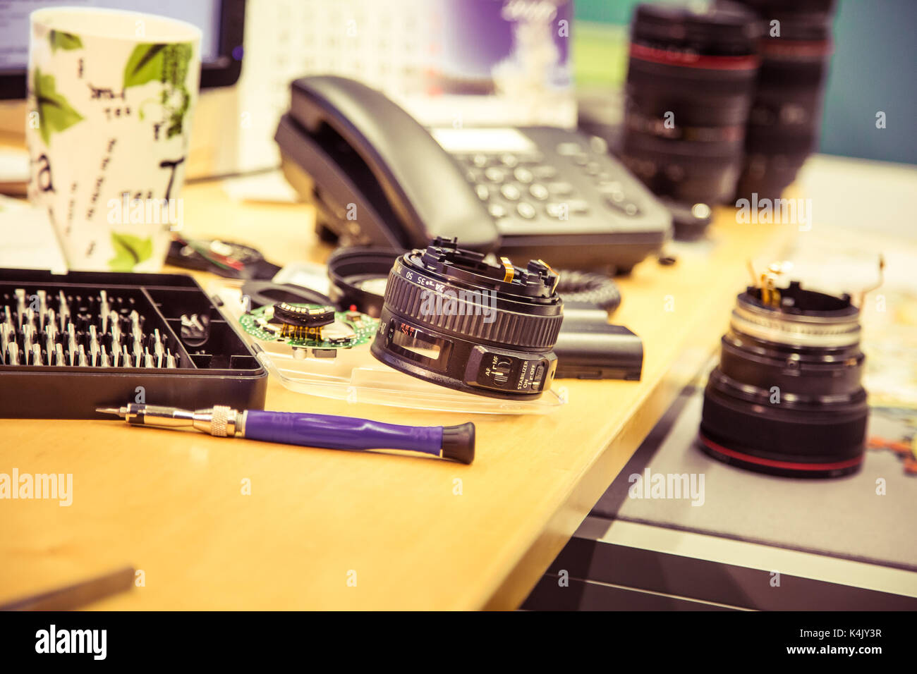 A man fixing photo camera lens on an office table Stock Photo - Alamy