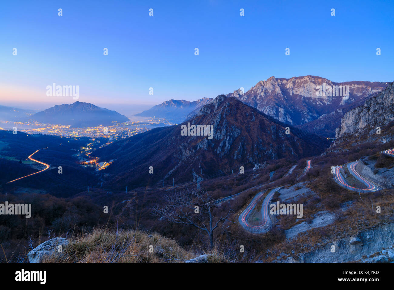 Dusk on the illuminated city of Lecco seen from the road to Morterone ...