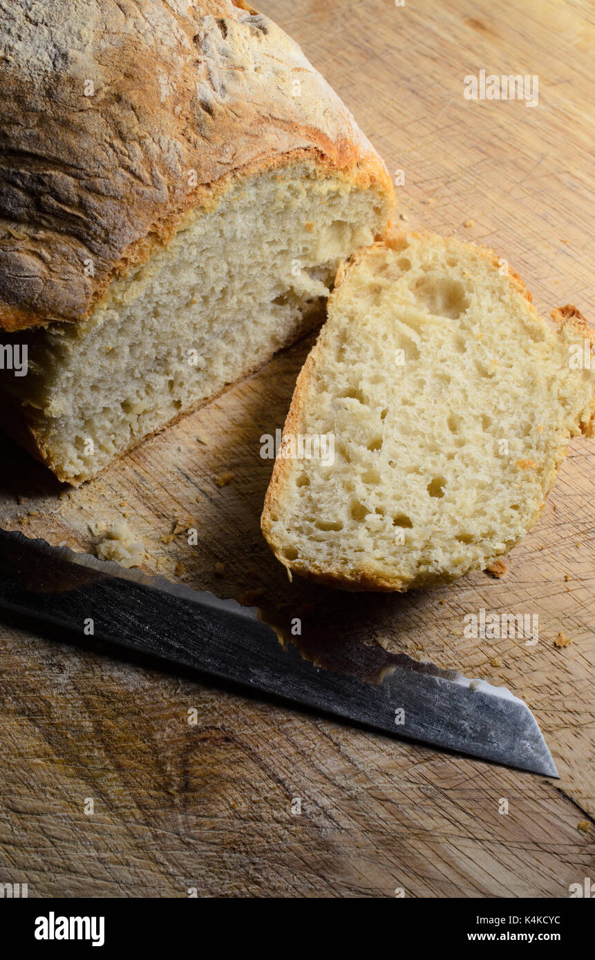 Freshly baked loaf of bread, shot from above. First slice cut and lying ...