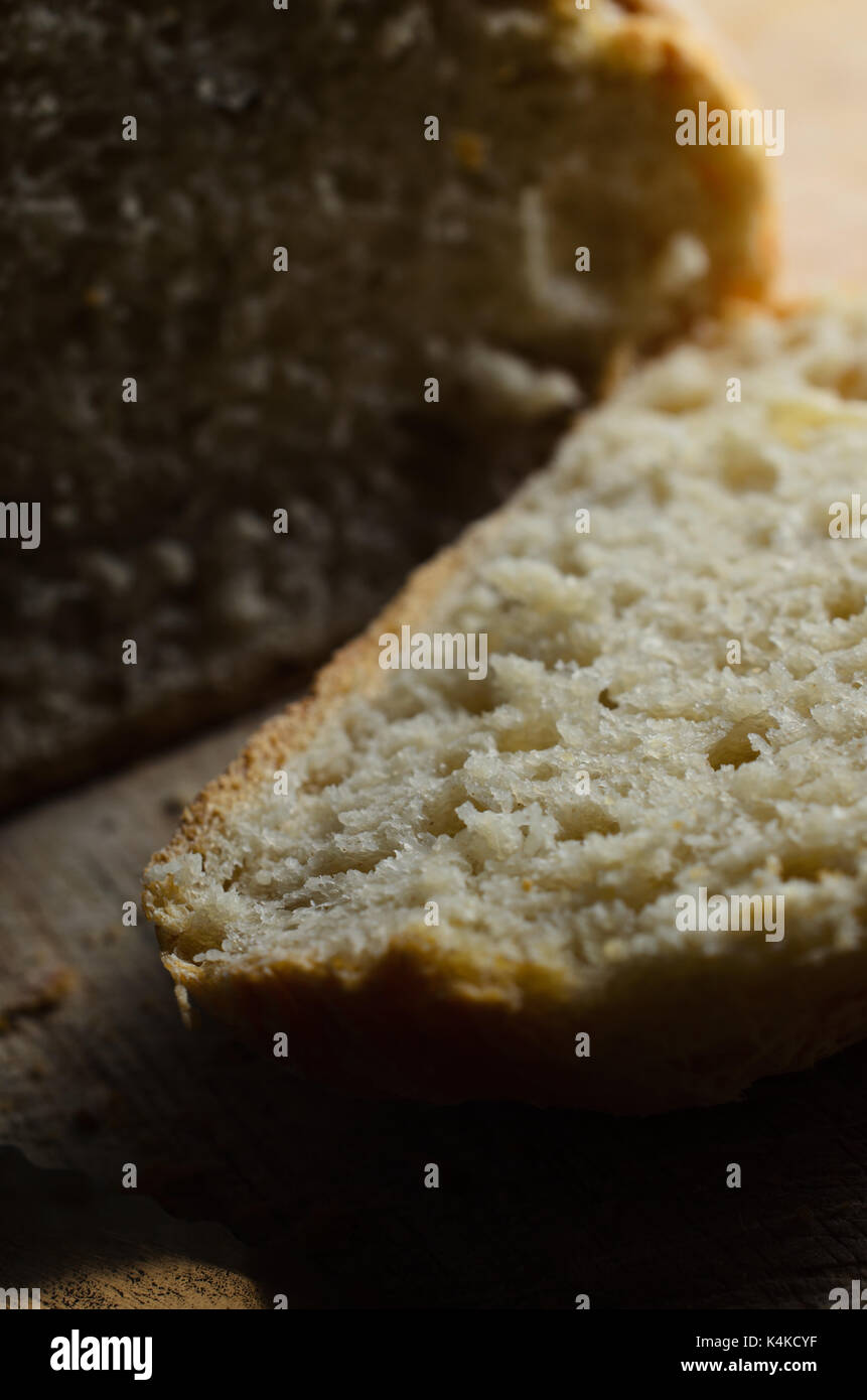 Freshly baked loaf of bread, with first slice cut and lying face up on ...