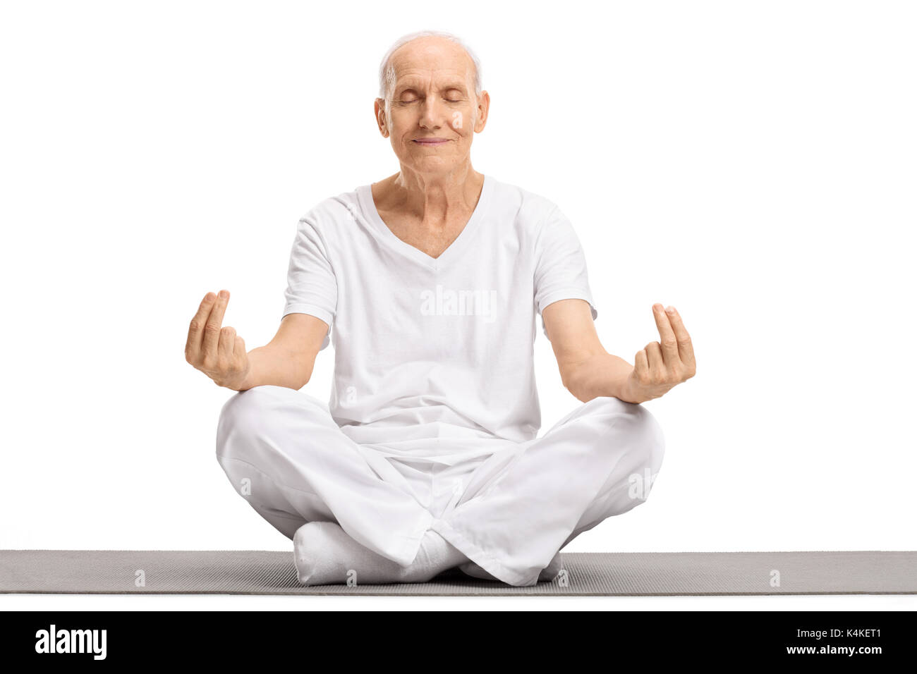 Elderly man meditating on an exercise mat isolated on white background ...