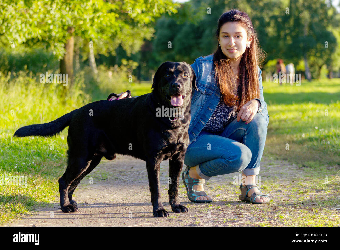 Beautiful young woman posing with her black labrador retriever on the ...