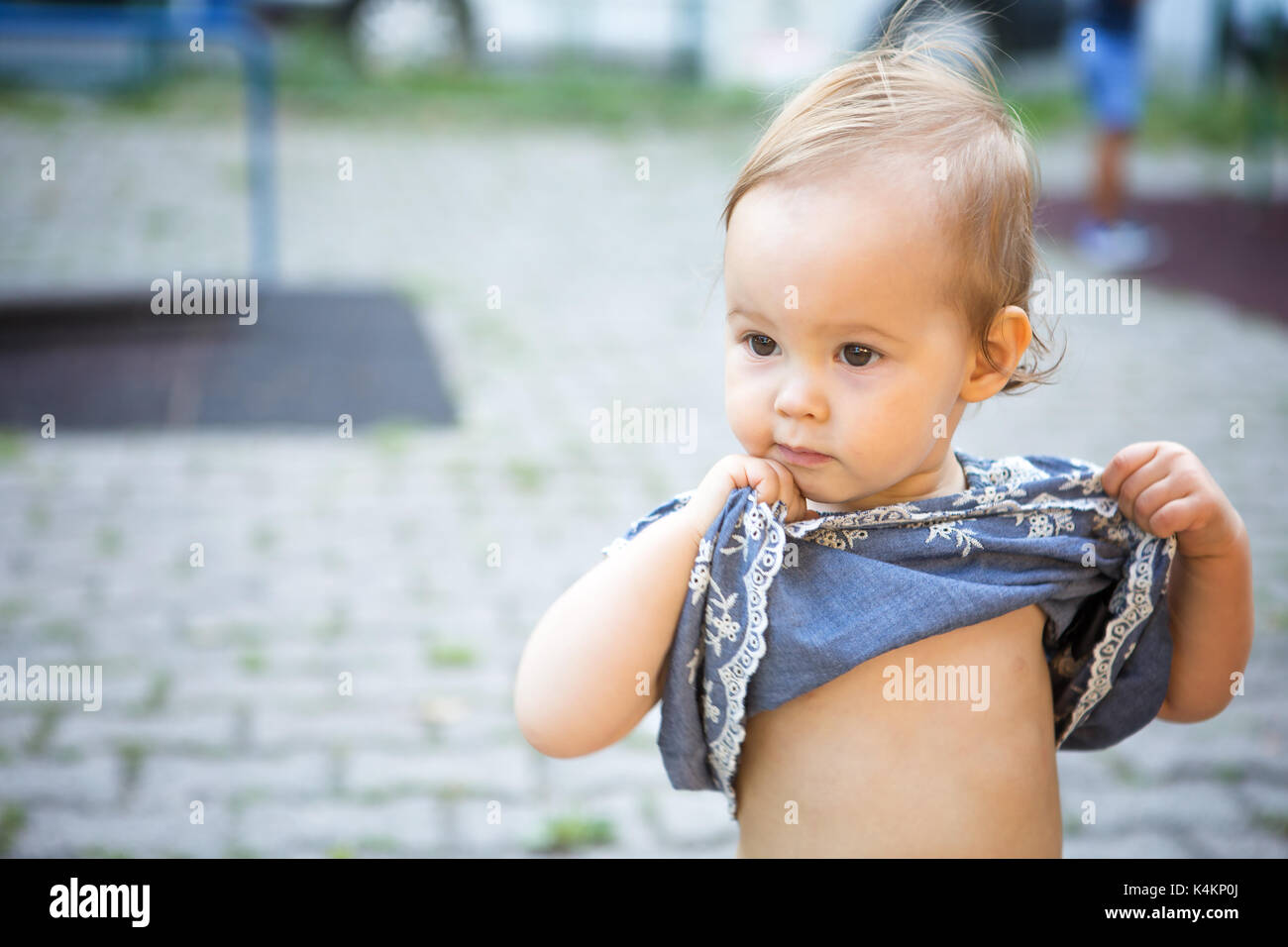 Baby girl playing on the children's playground and pulling her dress ...