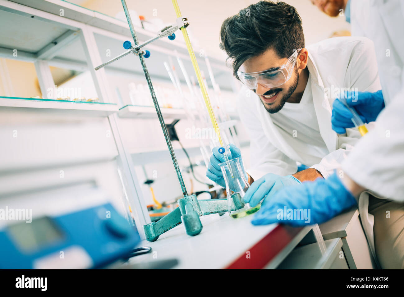 Young smiling student in white coat doing chemical tasks Stock Photo ...